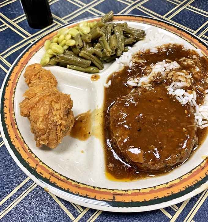 A divided plate that unites all the best Southern comfort foods: hamburger steak swimming in gravy alongside green beans and fried chicken.