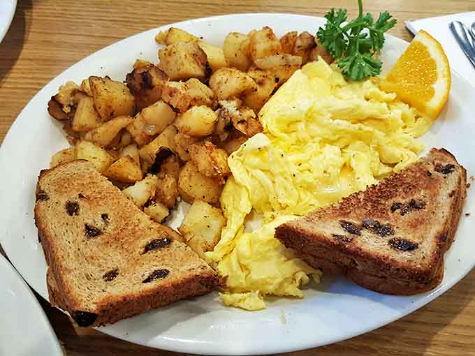 Breakfast simplicity perfected: fluffy scrambled eggs, perfectly crisped home fries, and raisin toast that makes you wonder why you ever eat anything else before noon.