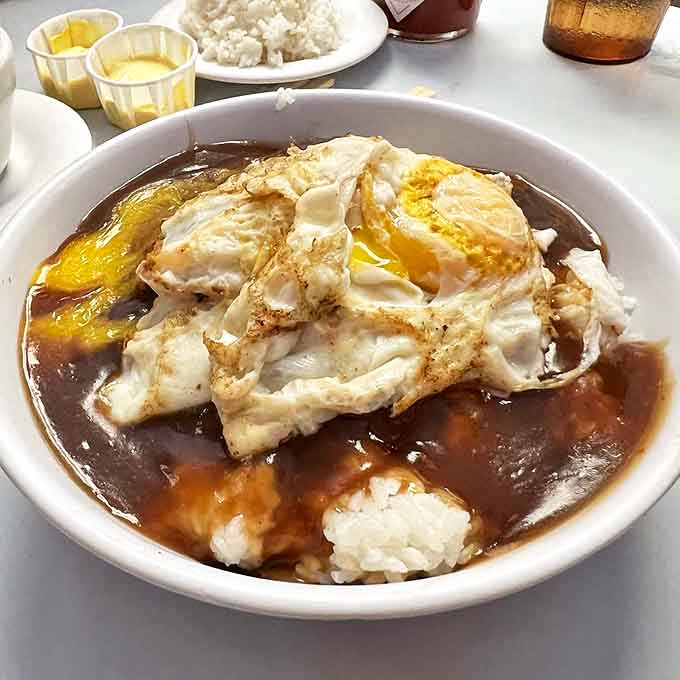 Loco moco with perfectly runny eggs atop a mountain of gravy-soaked rice. Comfort food that hugs your soul and doesn't let go.