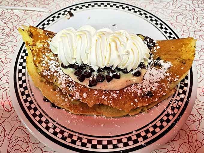 This isn't just a pancake; it's a fluffy disc of joy that requires its own zip code, topped with a cloud of whipped cream and berries.