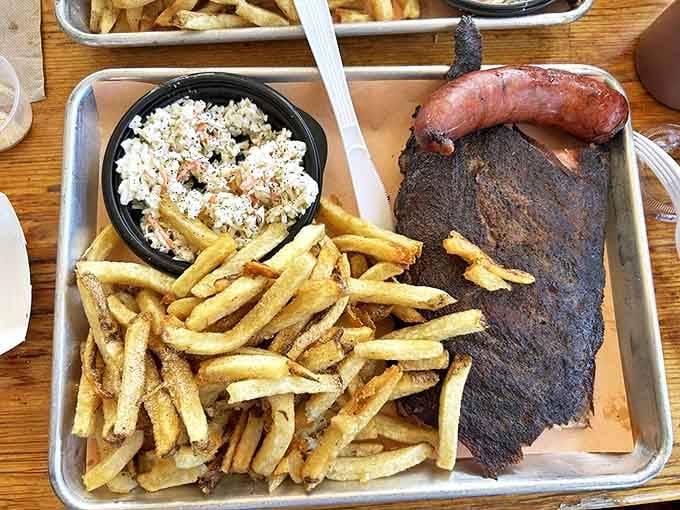 Barbecue artistry on display&mdash;a brisket with that coveted smoke ring sitting alongside fries and rice, a symphony of textures on a metal tray.