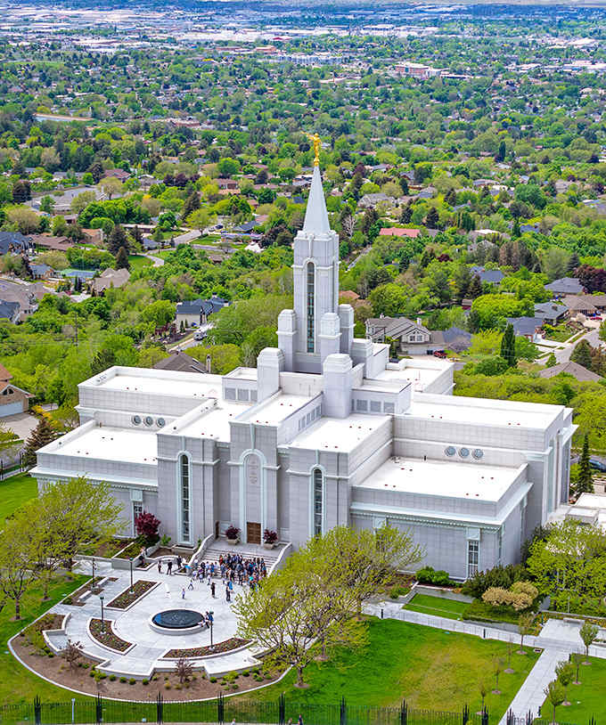 The Bountiful Temple rises like a beacon of peace, its white spire reaching toward those magnificent mountain peaks.