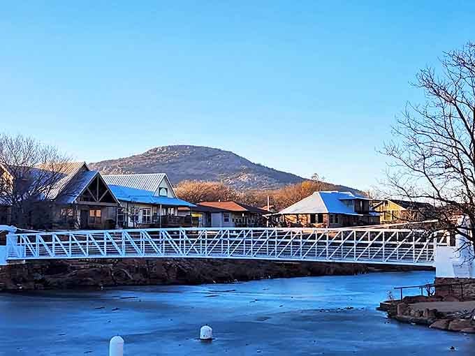 A bright white bridge stretches across the water, offering a perfect vantage point for the scenic mountains of Medicine Park.