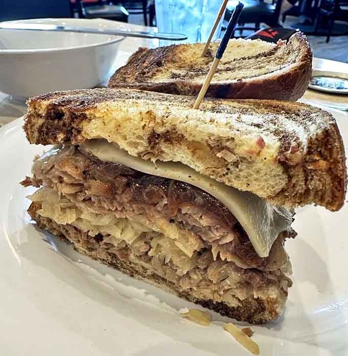 The Reuben arrives like a skyscraper of flavor &ndash; corned beef, sauerkraut, and Swiss cheese melding together in a sandwich that demands both hands and your full attention.