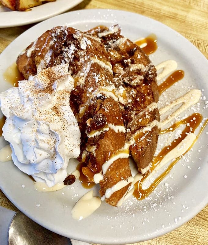 French toast that makes you question every other breakfast you've ever had &ndash; caramelized, cinnamon-kissed, and draped in whipped cream like a morning dessert revolution.