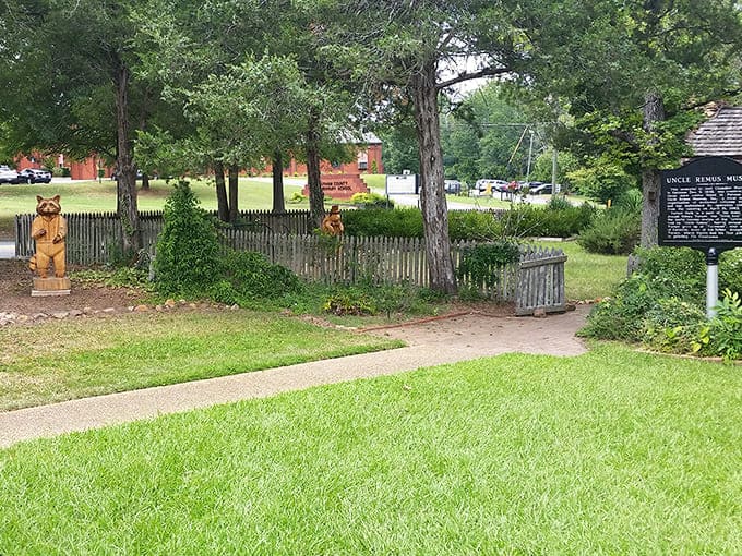 Whimsical wooden carvings welcome visitors to the Uncle Remus Museum, where folklore comes alive amid picket fences and Southern greenery.