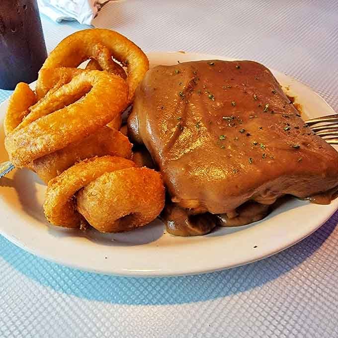 Open-faced meatloaf sandwich with onion rings that could double as edible bracelets—comfort food that hugs you from the inside out.