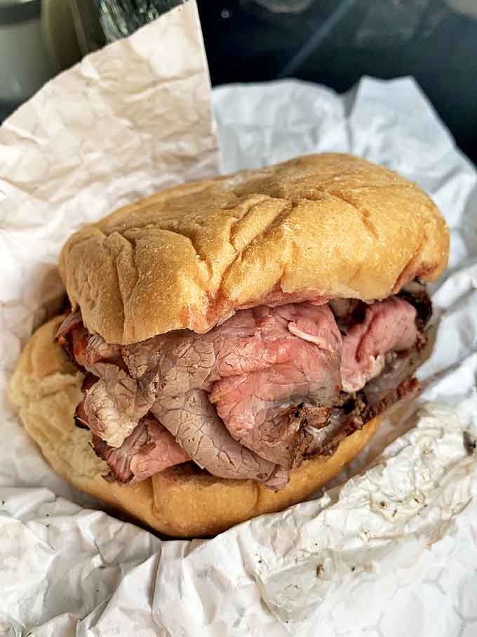 The cross-section reveals the truth: perfectly pink beef, sliced whisper-thin, piled higher than your weekend expectations.