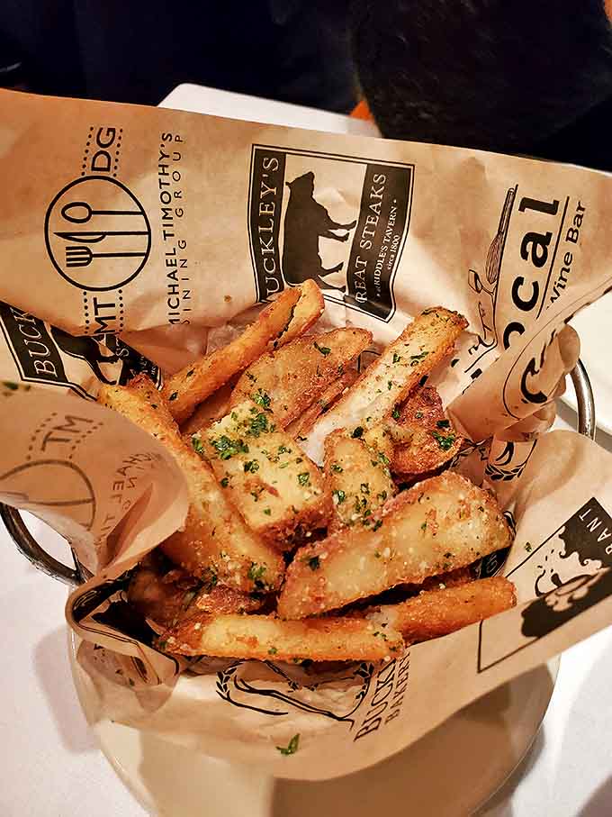 Truffle fries: where potato meets luxury in a paper-lined basket. The herbs aren't garnish—they're little green permission slips to indulge.