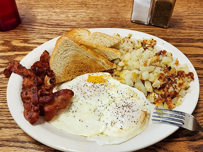The holy trinity of breakfast: eggs with just-set whites and runny yolks, bacon with that perfect crisp-chewy balance, and hash browns that crackle with each bite.
