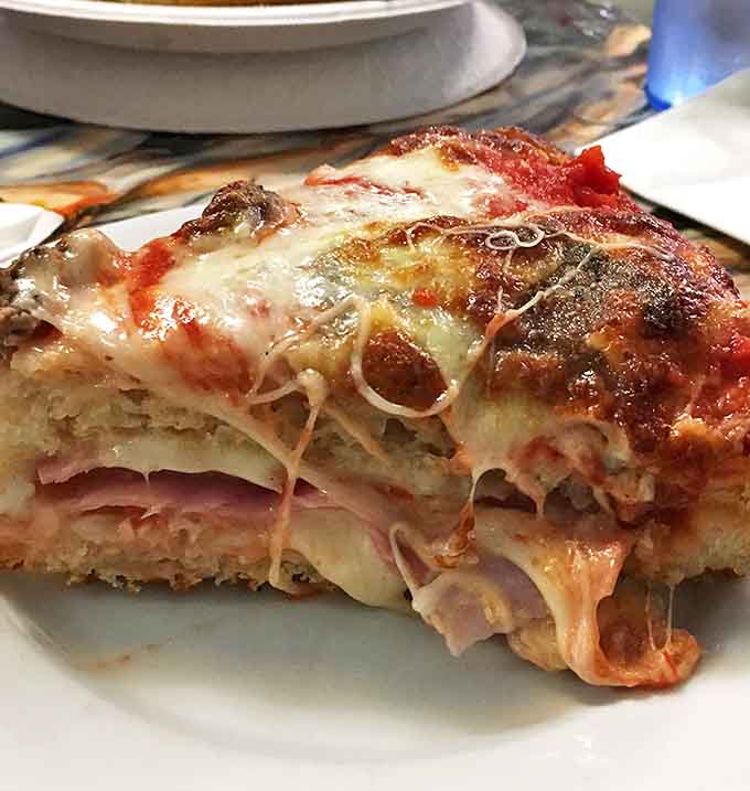 The cross-section tells the whole story &ndash; layers of cheese, toppings, and sauce nestled in a crust that's both substantial and sublime.