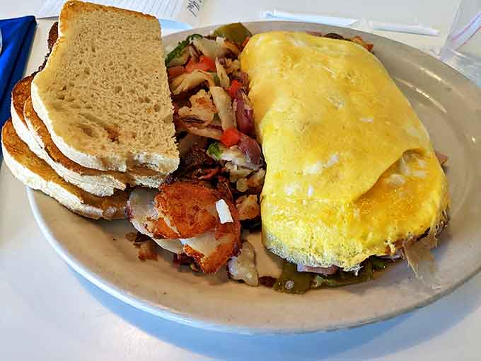 This omelet doesn't just sit on the plate – it commands it, with a supporting cast of perfectly seasoned home fries.