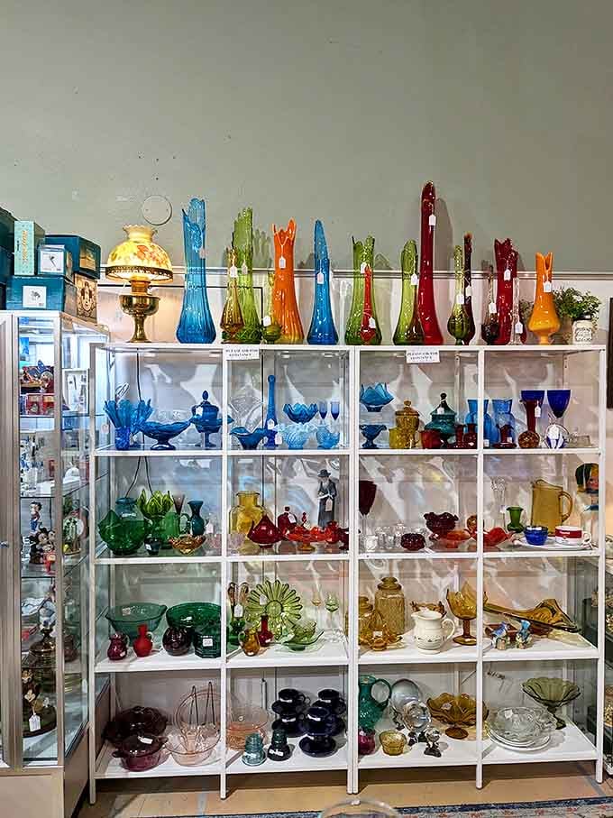 A rainbow of vintage glassware catching light like a jewelry store for giants. Each colorful vase has outlived trends, moves, and probably several well-intentioned house cleanings.