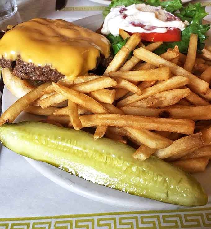 The cheeseburger that launched a thousand napkins, served with a pickle spear that's practically begging to be the first bite.