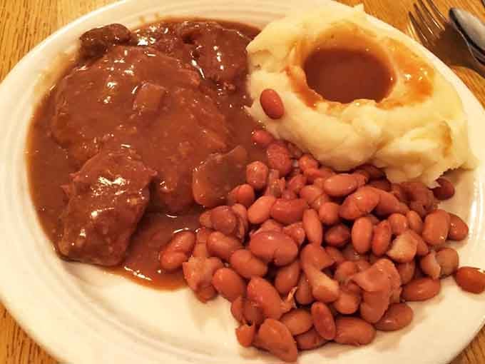 Country-style steak swimming in rich brown gravy alongside pintos and potatoes &ndash; the holy trinity of Southern comfort that makes Monday feel like Sunday dinner.