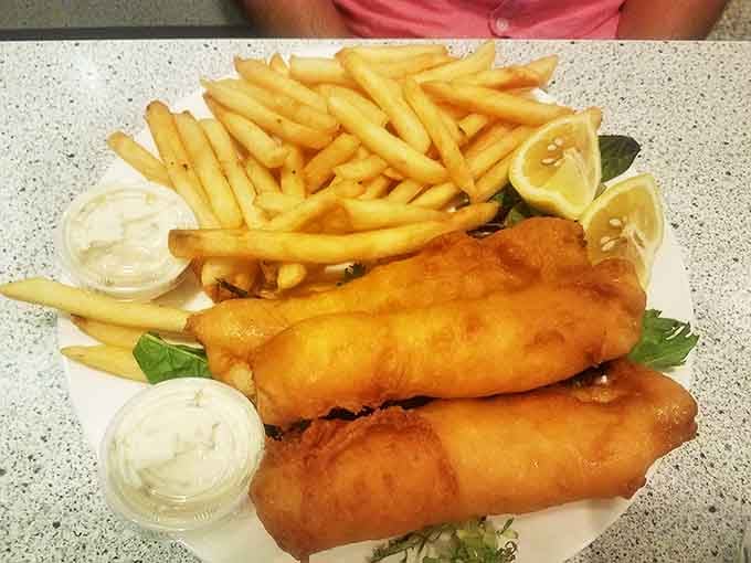 The fish and chips arrive with that audible crunch that signals the start of a beautiful friendship between seafood and hot oil.