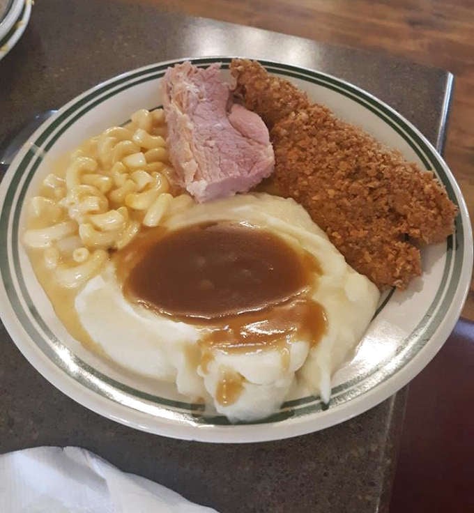 Mashed potatoes cradling a pool of gravy like nature's perfect edible bowl, flanked by mac and cheese that means business.