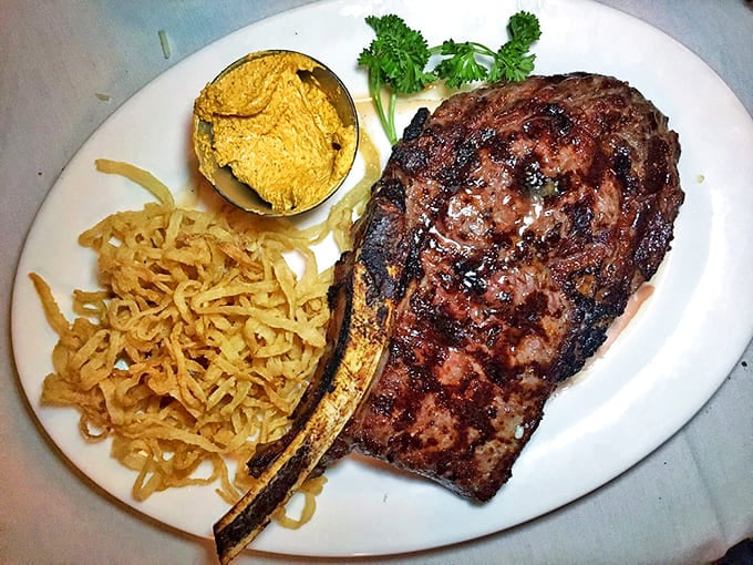 A bone-in ribeye with crispy onion straws&mdash;carnivore poetry on a plate that makes vegetarians question their life choices.