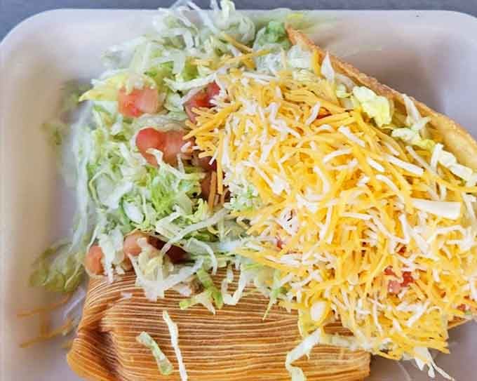 The classic combo plate—where a tamale and taco become best friends on a bed of shredded lettuce. It's the buddy comedy of lunch options.