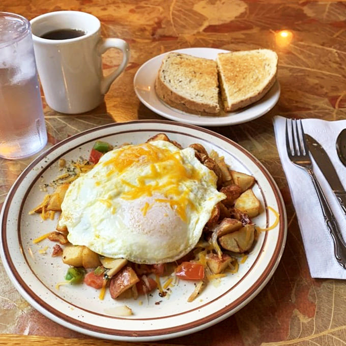 Eggs perched majestically atop a mountain of potatoes and veggies—proof that sometimes the best view at breakfast isn't out the window.