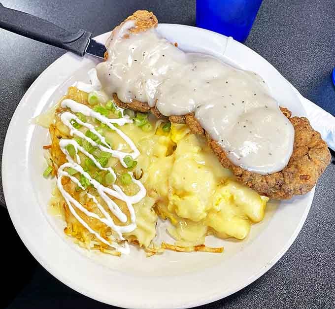 This chicken fried steak is living its best life under a blanket of country gravy, with hash browns dressed for their own special occasion.