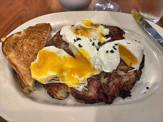 Corned beef hash with eggs that burst like the finale of a breakfast fireworks show. The toast stands by, ready to soak up the golden deluge.
