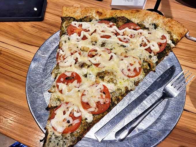 The pesto pizza showcases fresh tomatoes and herbs, proving that sometimes the simplest combinations create the most profound pizza experiences.