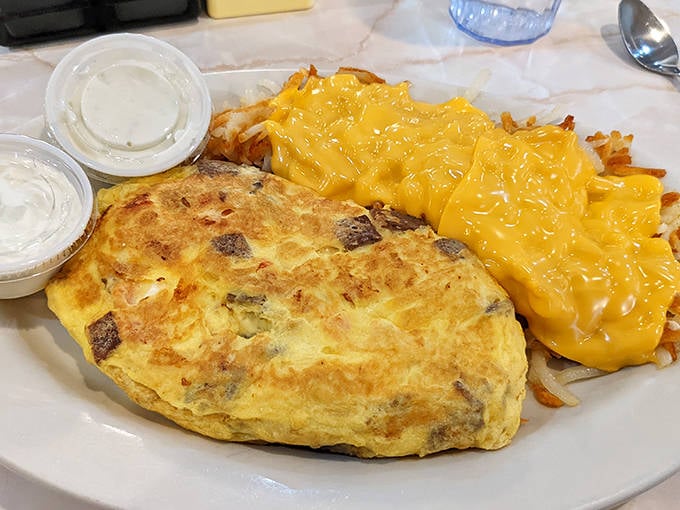 Breakfast perfection: a fluffy omelet alongside cheese-smothered hash browns &ndash; the morning duo that's worth setting your alarm for.