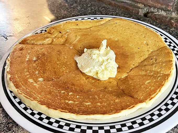 This pancake isn't just large—it's downright territorial, with a pat of butter melting into its golden landscape like a delicious sunrise.