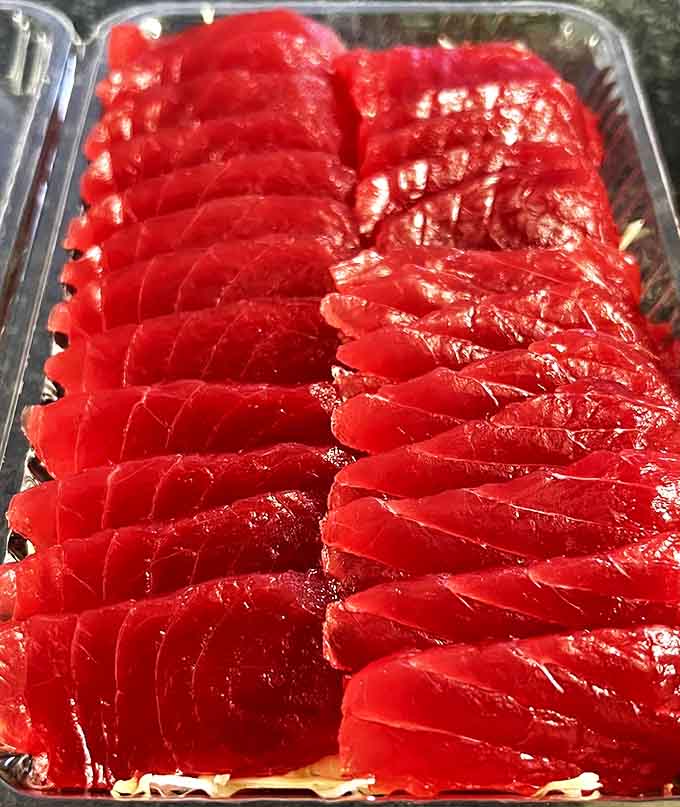 Ruby-red slices of premium ahi sashimi laid out with the precision of a jeweler, showcasing the ocean's most precious culinary gem.