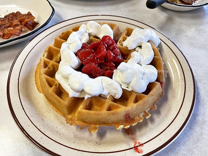 A waffle crowned with whipped cream and strawberries &ndash; because sometimes breakfast deserves to dress up and feel fancy too.