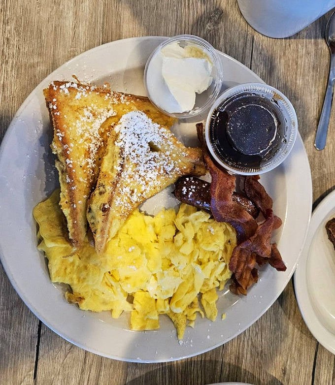Breakfast done right: French toast dusted with powdered sugar, scrambled eggs, and bacon&mdash;the holy trinity of morning happiness.