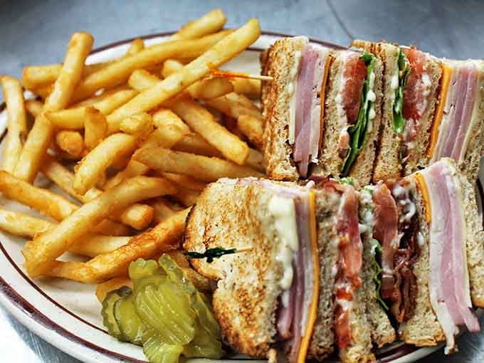 The club sandwich stands tall and proud, layers stacked with military precision. Those fries aren't just a side&mdash;they're an essential supporting character.