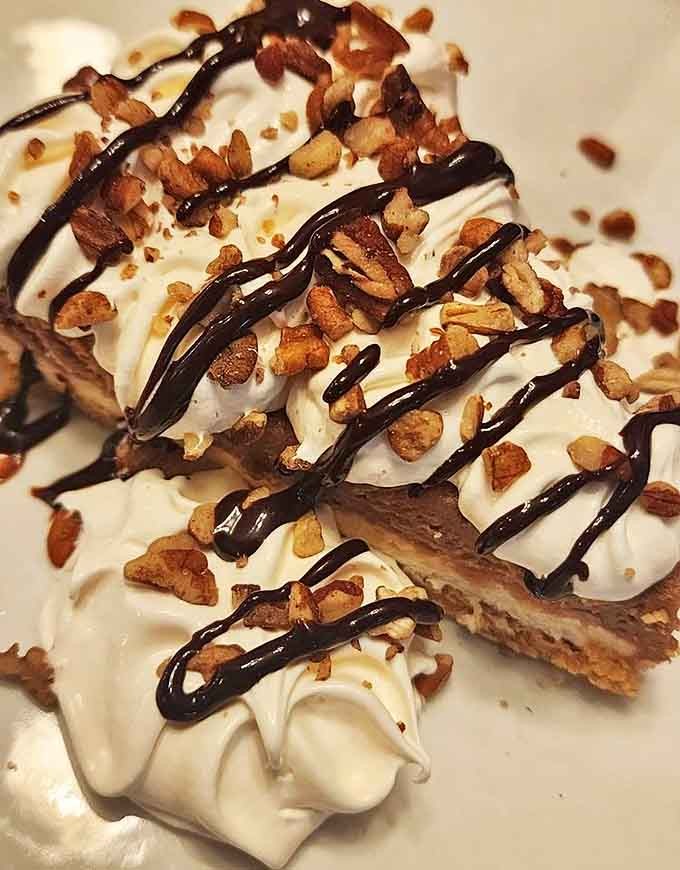 This isn't just dessert&mdash;it's a sweet, creamy architectural marvel topped with chocolate drizzle and nuts that demands to be photographed before devoured.