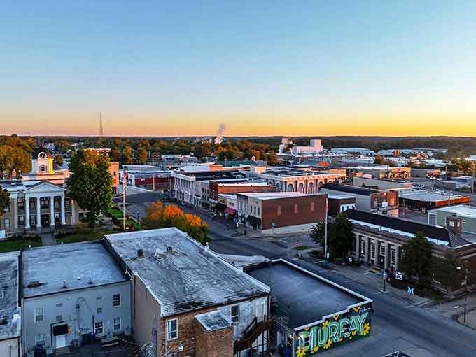 The sun sets over Murray's downtown, casting a golden glow across the historic buildings and tree-lined streets.