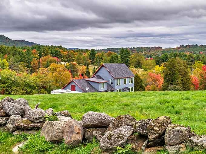 A classic New Hampshire homestead nestled among fall foliage with stone walls that have witnessed centuries of changing seasons.