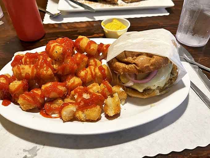 Tater tots wearing their Sunday best—dressed in a sassy red sauce and escorting what appears to be the burger equivalent of a prom king.