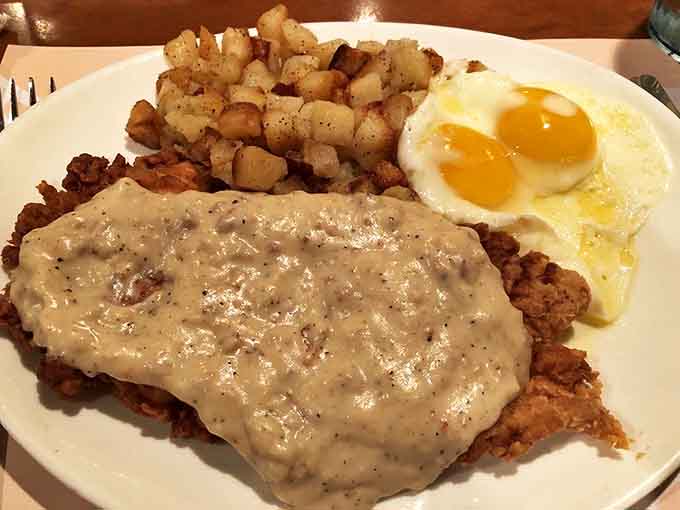 Country fried steak smothered in gravy with sunny-side-up eggs standing by. This plate doesn't just feed you – it hugs you from the inside.