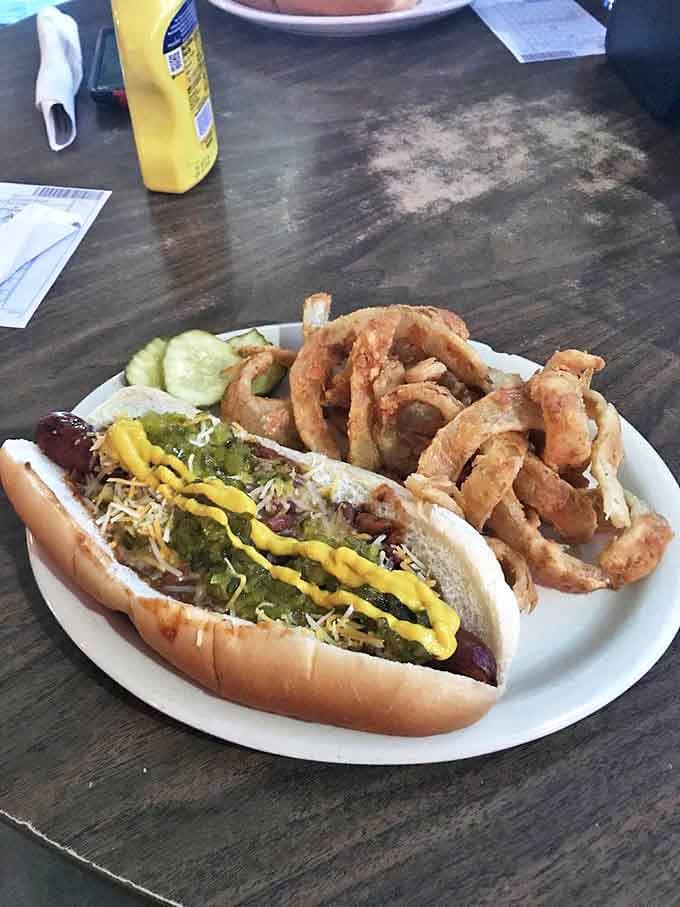 The humble hot dog elevated to art form &ndash; dressed to impress with chili, cheese, and mustard, accompanied by onion rings that deserve their own fan club.