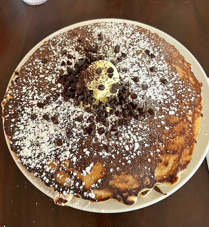 A chocolate chip pancake so perfect it deserves its own Instagram account. Powdered sugar snow on a breakfast mountain.