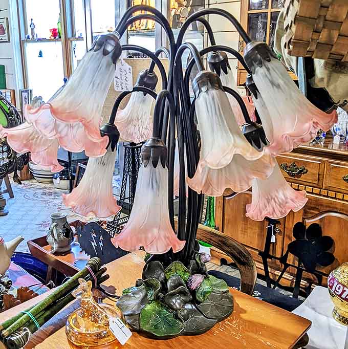This lily lamp would make Tiffany himself nod in approval. Delicate pink glass petals transform ordinary light into something that belongs in a Victorian novel.