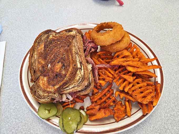 A Reuben sandwich with sweet potato fries and onion rings&mdash;proof that sometimes the best lunch is the one that requires both hands and extra napkins.