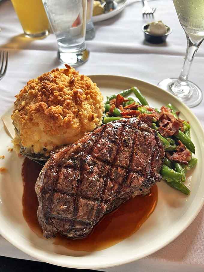 Not just a steak, but a complete landscape—charred peaks of beef, a forest of green beans, and a loaded potato that could be its own meal.
