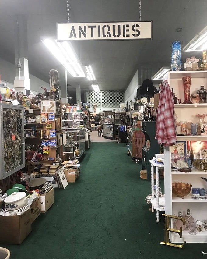 The "ANTIQUES" sign hangs like a promise, guiding you through a forest of memories and merchandise waiting to be rediscovered.