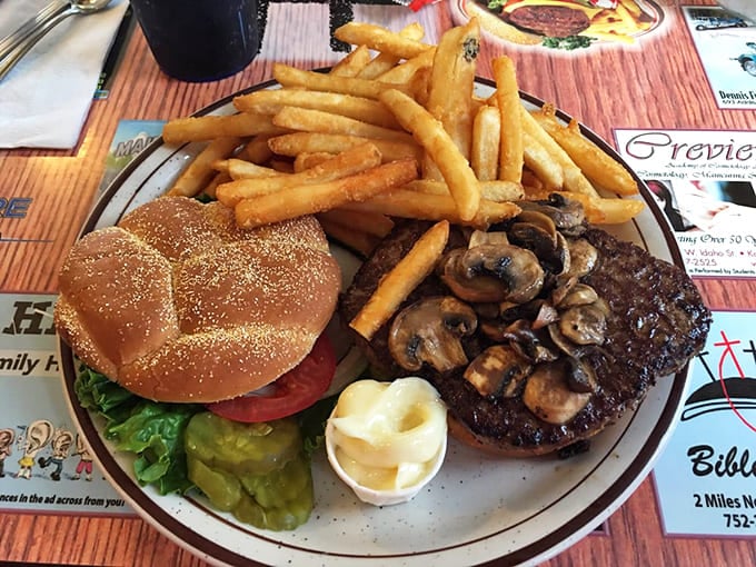 The Mushroom Swiss Burger arrives like a monument to beef perfection, with golden fries standing at attention alongside it.