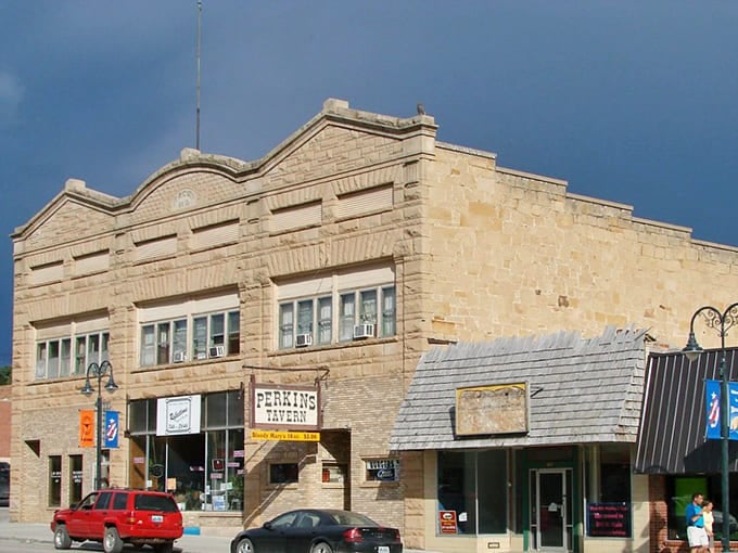 Historic stone buildings line Newcastle's main street, where Perkins Tavern welcomes locals under stormy Wyoming skies.