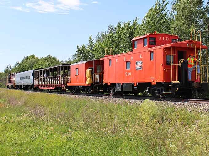 The iconic red caboose #510 rolls through Indiana countryside, a vibrant reminder of when these "crummies" served as mobile offices for train crews.