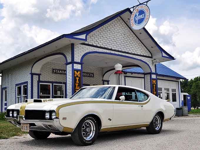 That gleaming white brick and blue trim combo hits different when there's a classic muscle car parked out front.