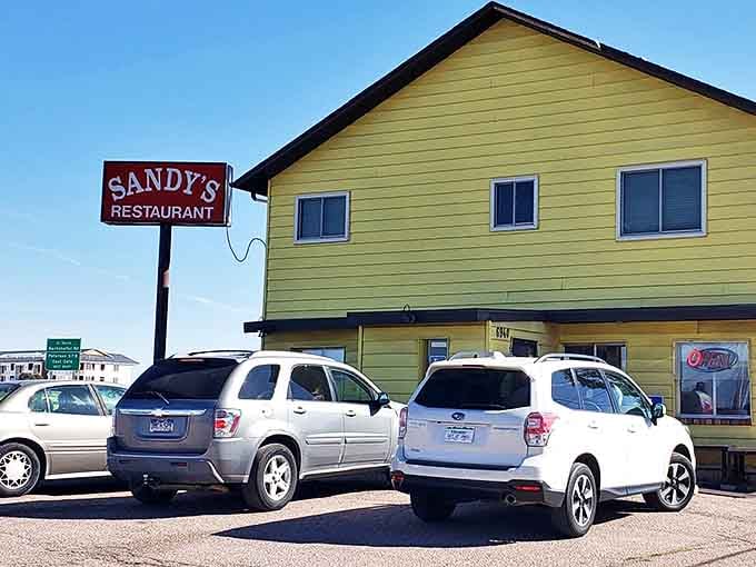 The iconic Sandy's sign stands tall against the Colorado blue sky, beckoning hungry travelers like a lighthouse for breakfast enthusiasts.