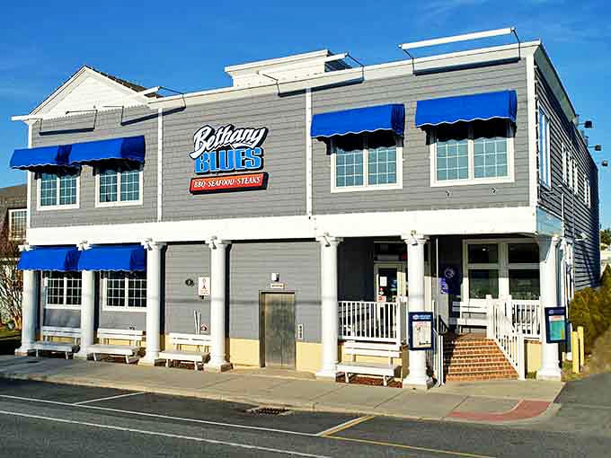 The coastal-chic exterior of Bethany Blues stands out with its distinctive blue awnings and gray shingles, beckoning hungry beachgoers like a barbecue lighthouse.